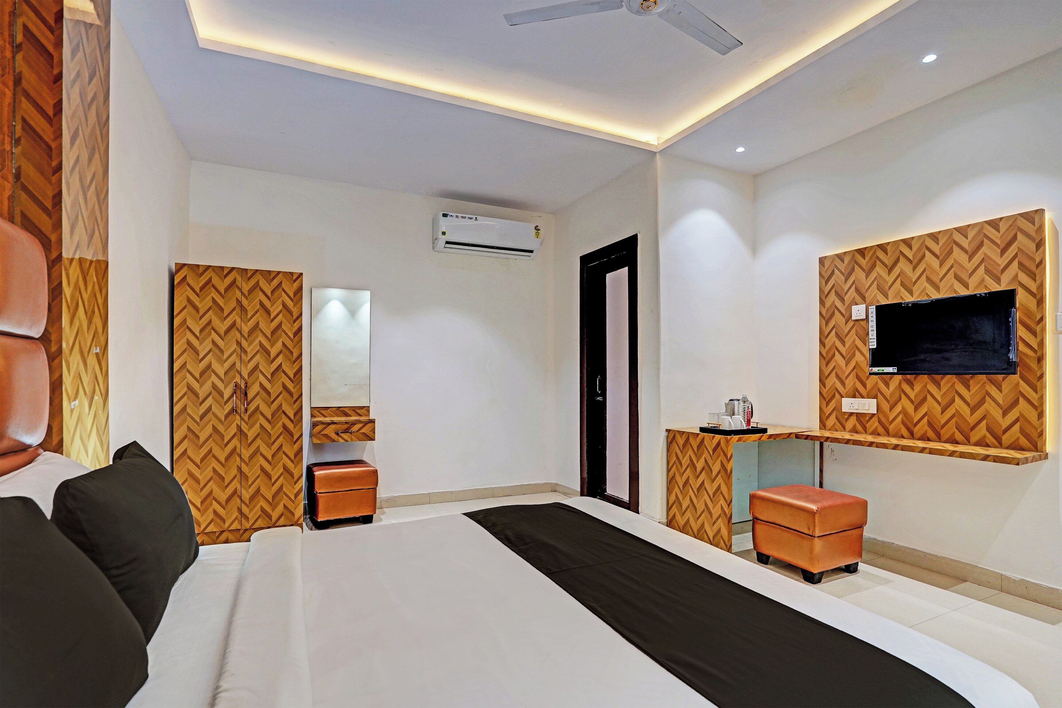Quarto de hotel moderno com cama, televisão na parede, escrivaninha e ar condicionado.