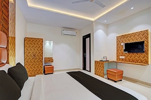 Quarto de hotel moderno com cama, televisão na parede, escrivaninha e ar condicionado.