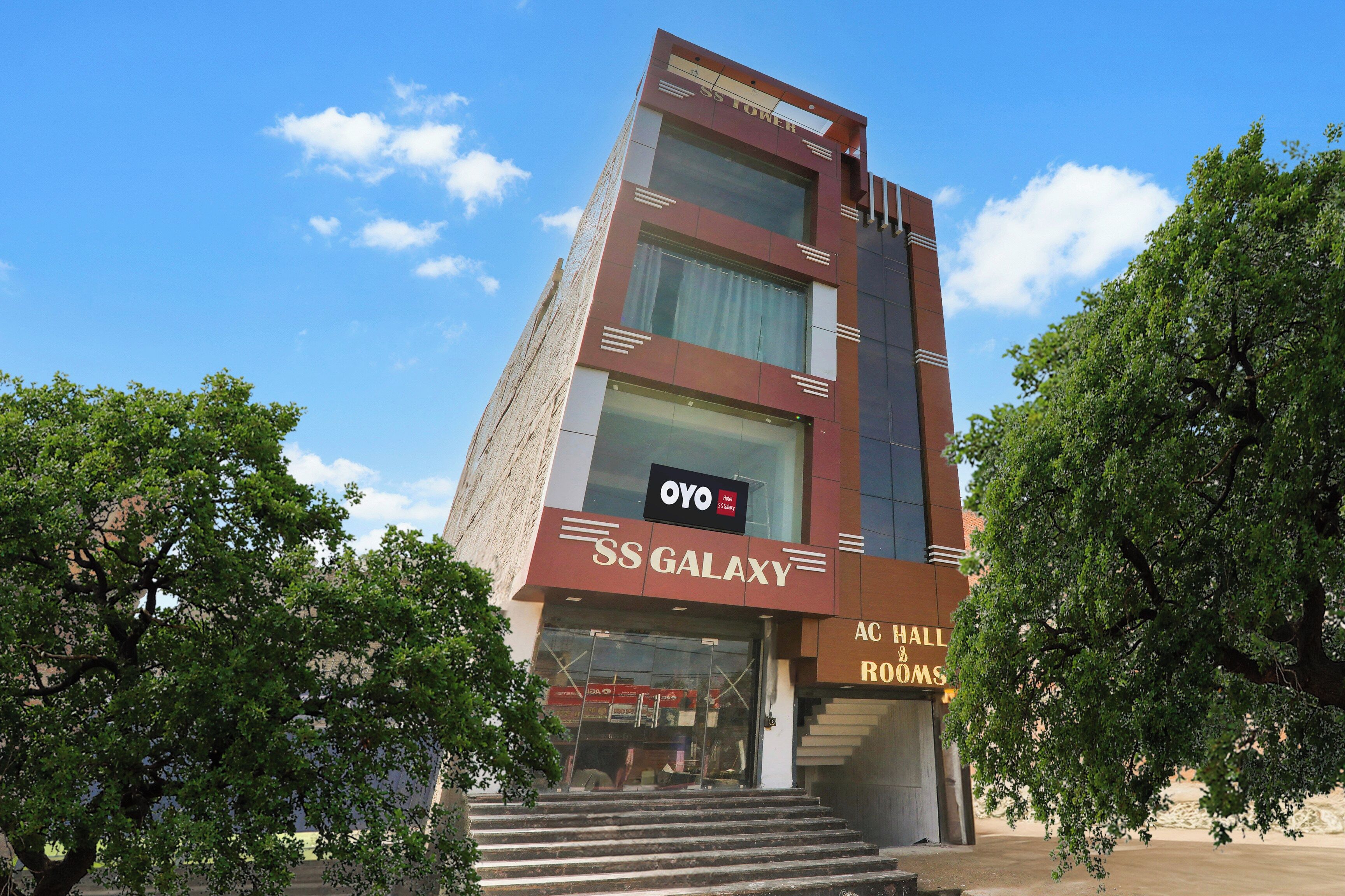 Um hotel chamado SS Galaxy com design moderno, apresentando uma escadaria imponente que leva à entrada.
