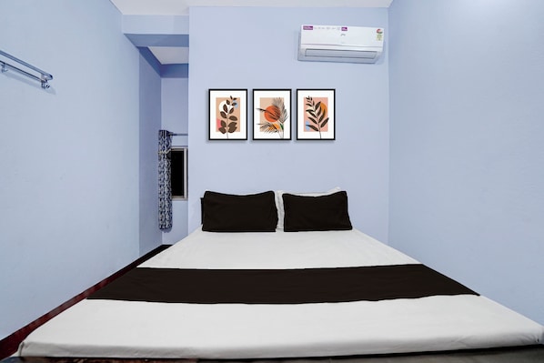 Um quarto com uma cama, uma janela com cortinas e três obras de arte emolduradas na parede.