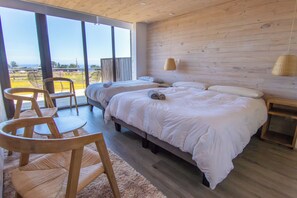 Quarto com duas camas, uma janela grande e vista para o exterior.