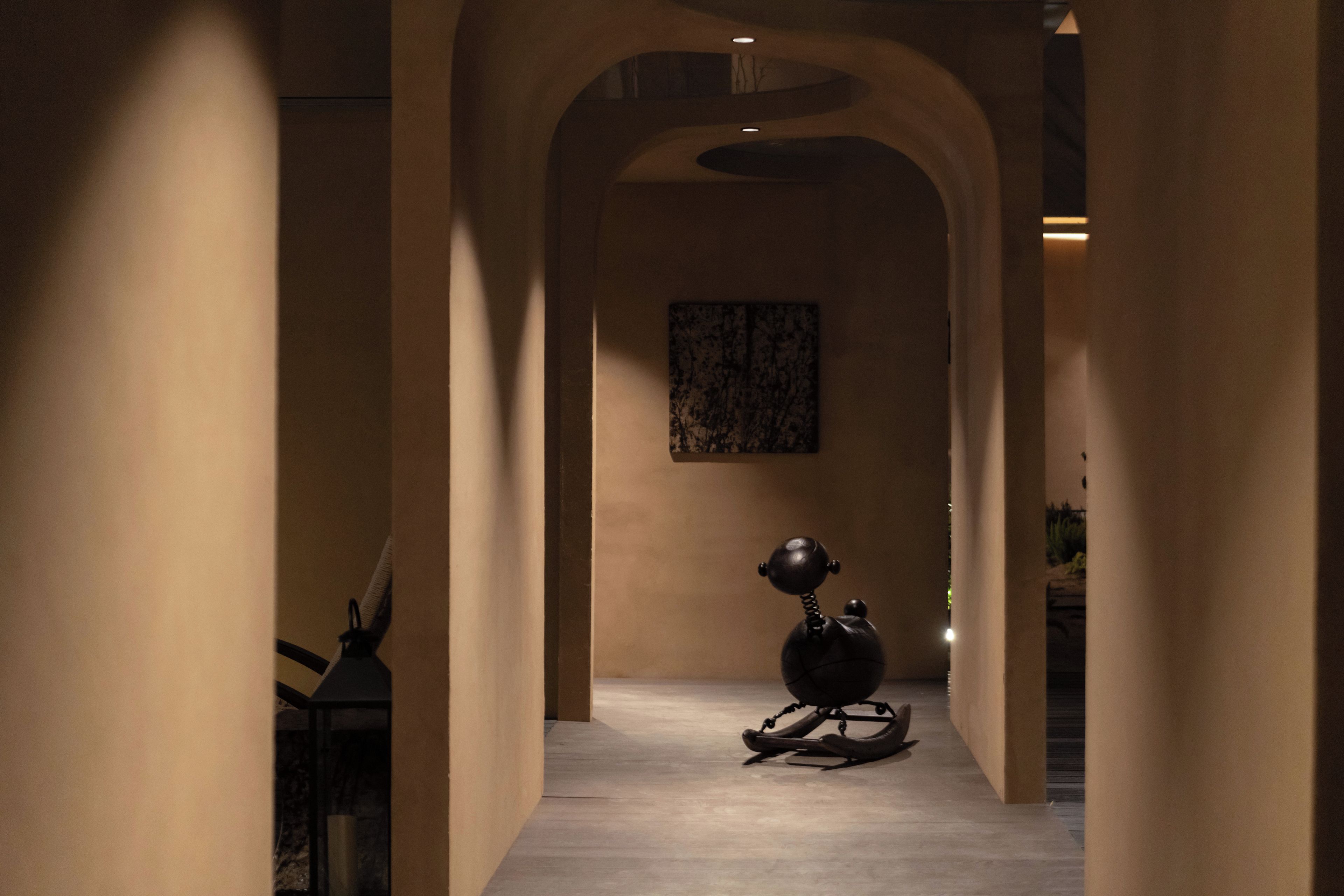 Um corredor com uma escultura e uma pintura na parede.
