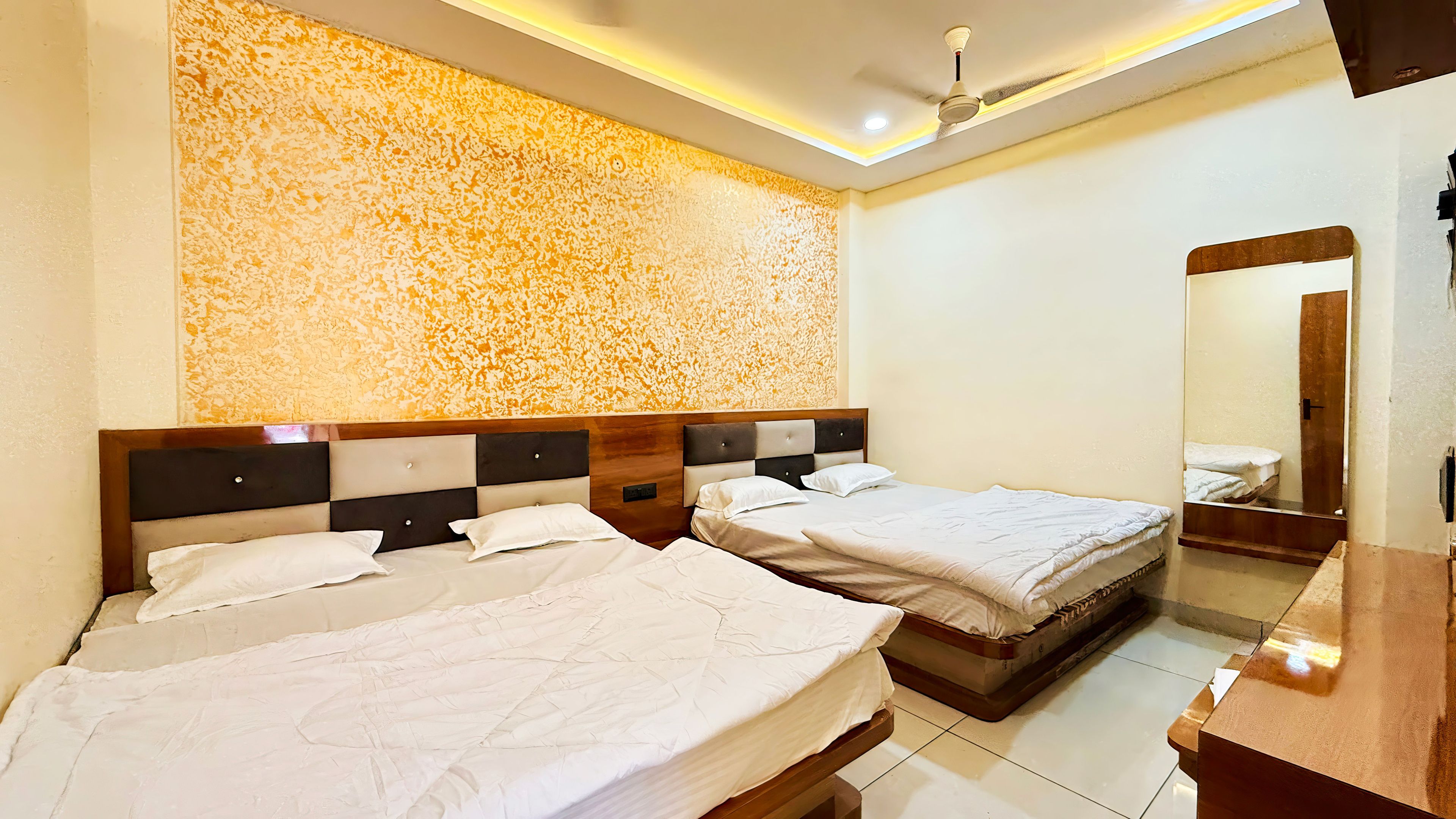 Quarto de hotel com duas camas, um ventilador de teto e um espelho grande.