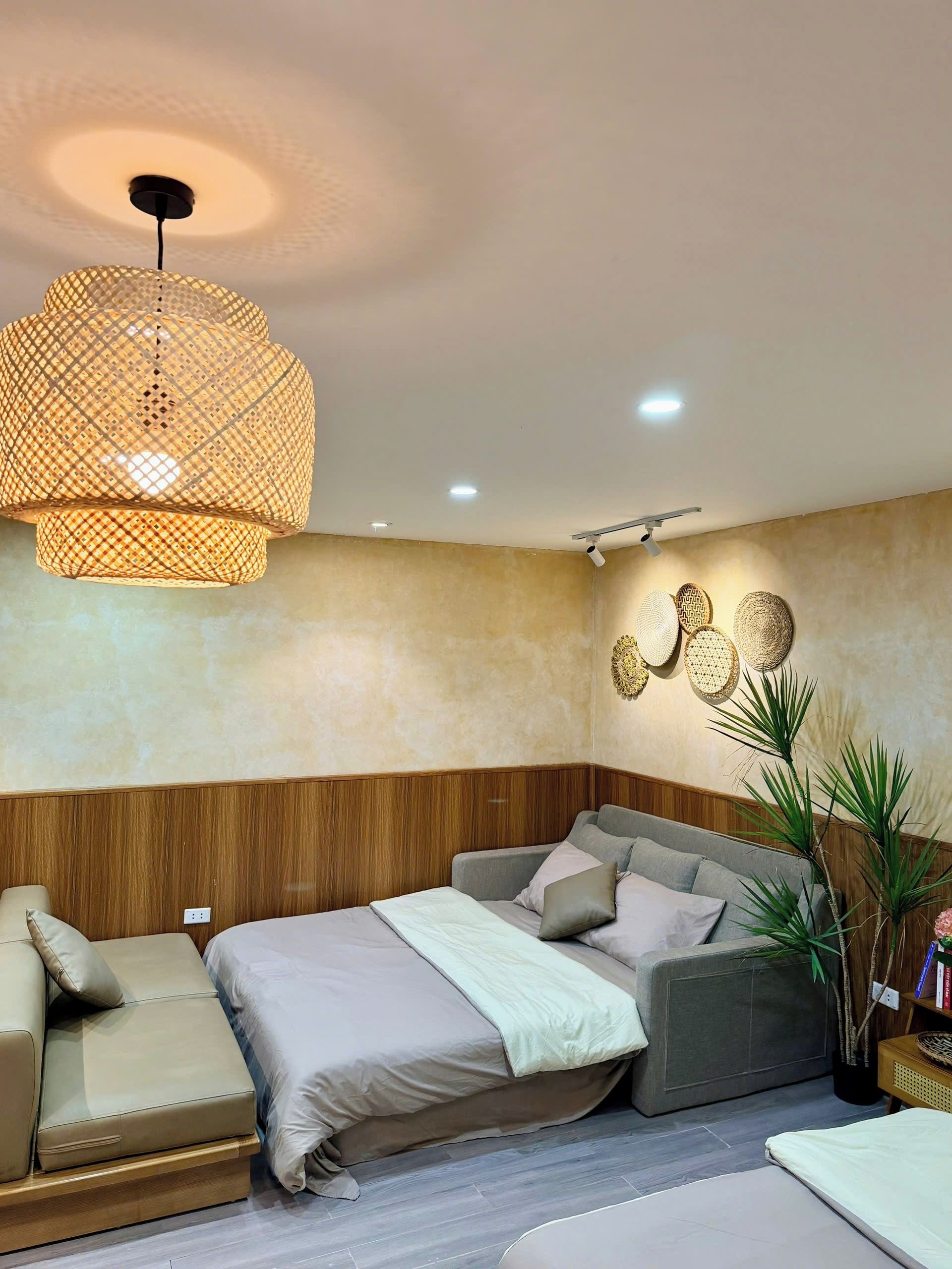 Quarto moderno com cama, dois sofás, luminária no teto e detalhes na parede.