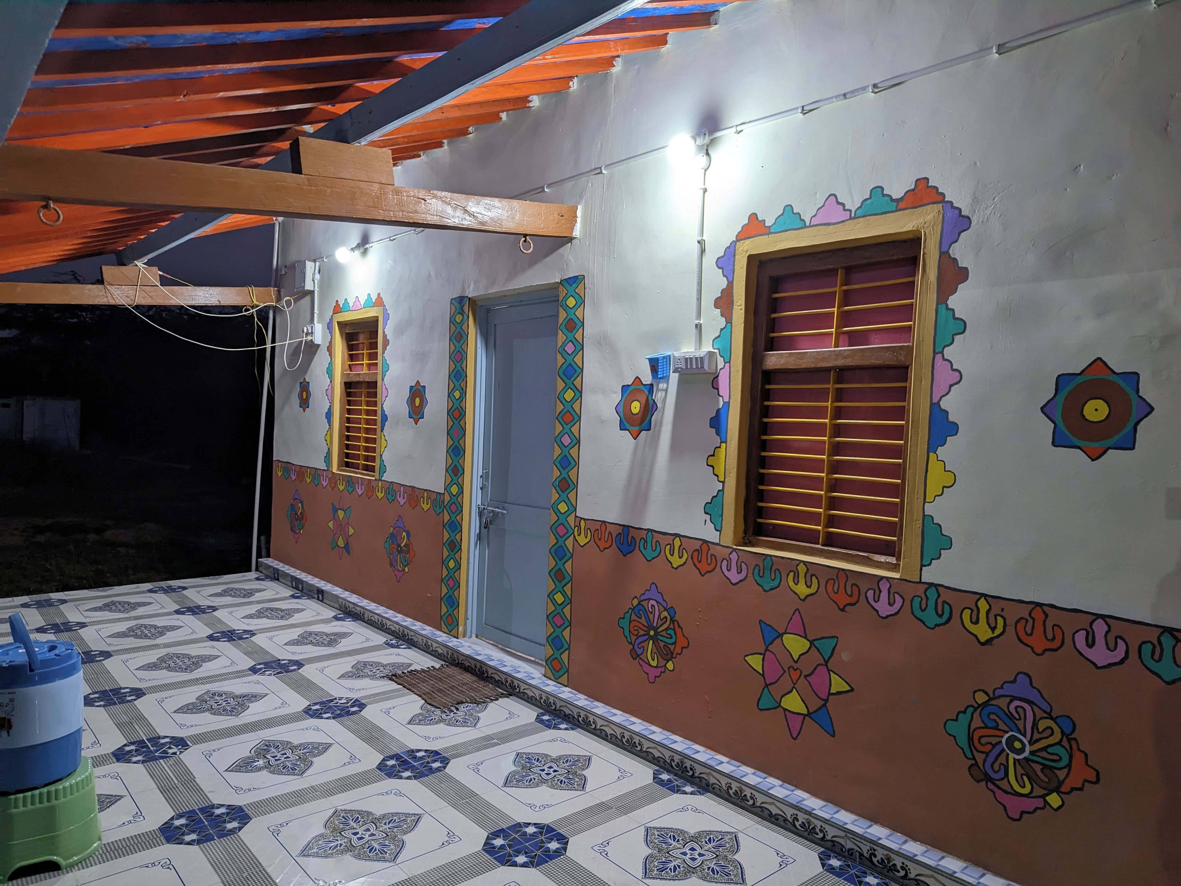 Um quarto com piso de azulejos, uma porta e uma janela com moldura decorativa.