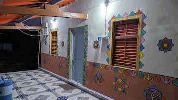 Um quarto com piso de azulejos, uma porta e uma janela com moldura decorativa.