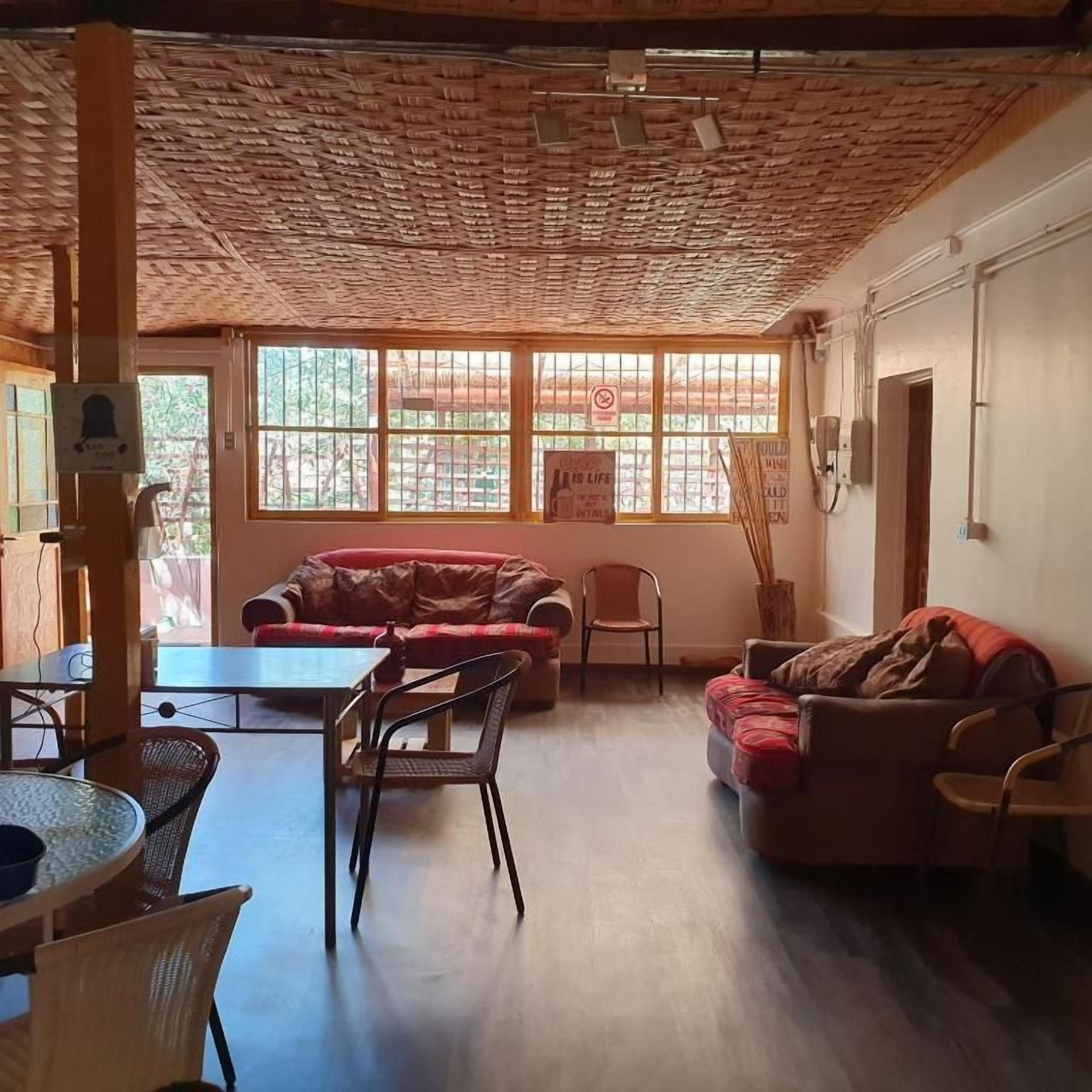 Quarto com teto de madeira, sofá vermelho, mesa de jantar com cadeiras e janela com vista.