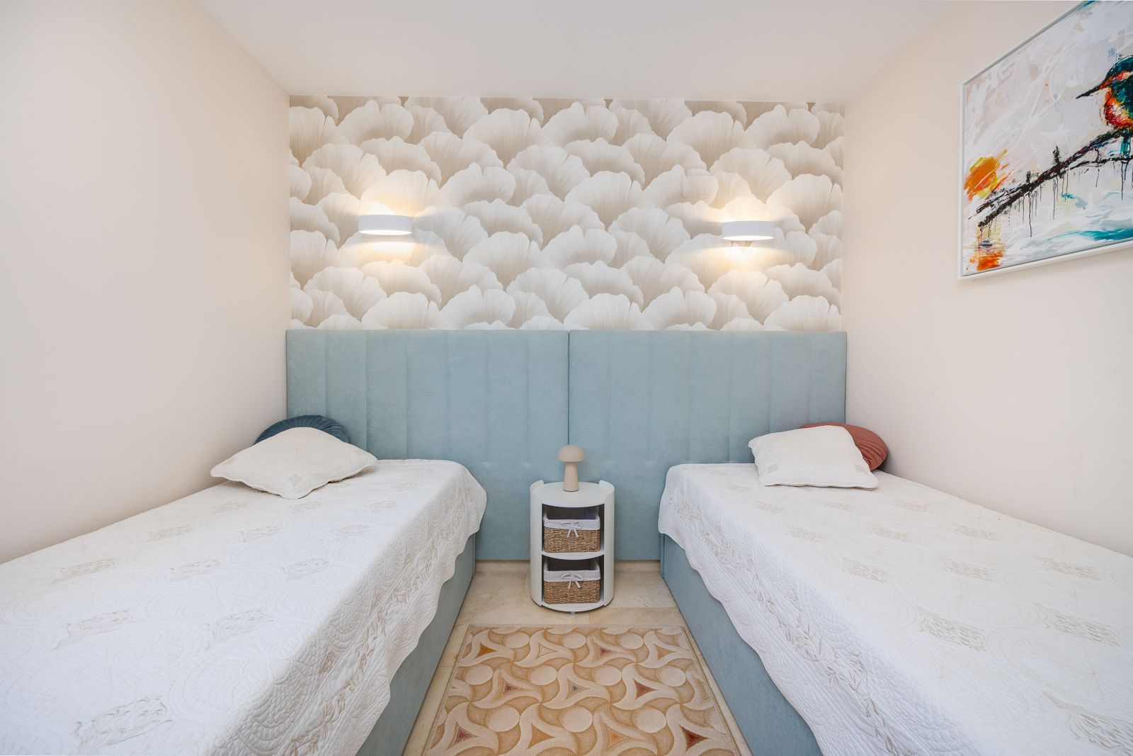 Quarto com duas camas, um painel decorativo e uma pintura.