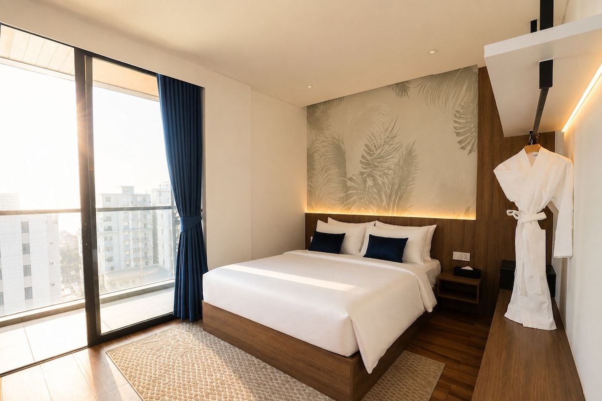 Quarto de hotel moderno com uma cama grande, vista para a cidade e um roupão pendurado na parede.