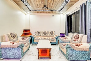 Sala de estar com sofá, duas poltronas, mesa de centro e ventilador de teto.
