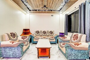 Sala de estar com sofá, duas poltronas, mesa de centro e ventilador de teto.