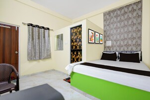 Quarto de hotel com cama, uma cadeira, guarda-roupa e espelho.