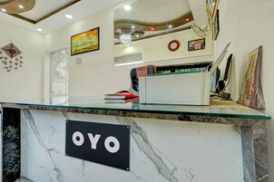 Bancada de recepção com uma placa indicando 'OYO' e um relógio acima.