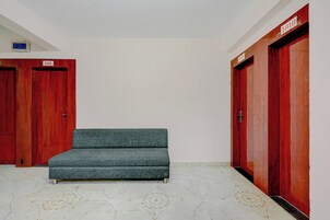 Quarto com sofá, duas portas de madeira e chão ladrilhado.
