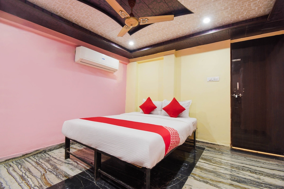 Quarto de hotel com cama, ventilador de teto, ar condicionado e porta.