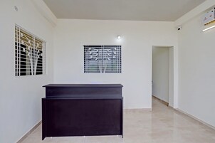 Quarto com um armário preto, uma janela com grade de metal e uma porta que dá para outro cômodo.