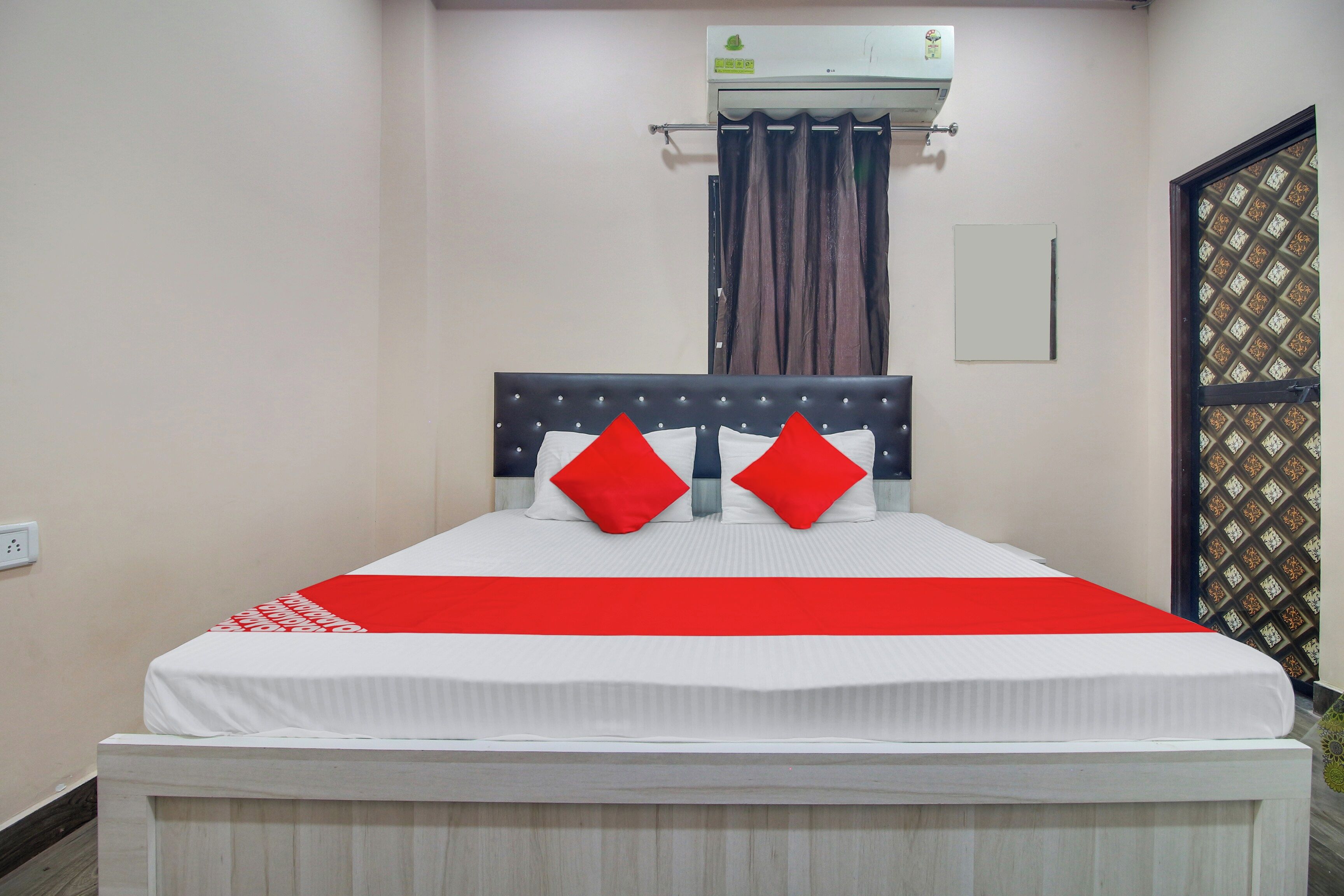 Cama com colcha branca e vermelha, duas almofadas vermelhas e cabeceira escura.