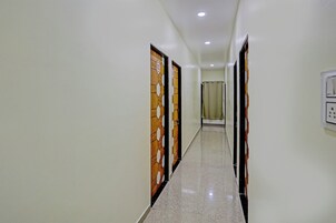 Um corredor com portas em ambos os lados, piso ladrilhado e luminária no teto.
