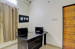 Quarto com escrivaninha, computador, impressora, porta e um letreiro com a palavra 'OYO'.