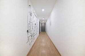 Um corredor com piso de madeira e paredes brancas, que leva a uma porta no final.