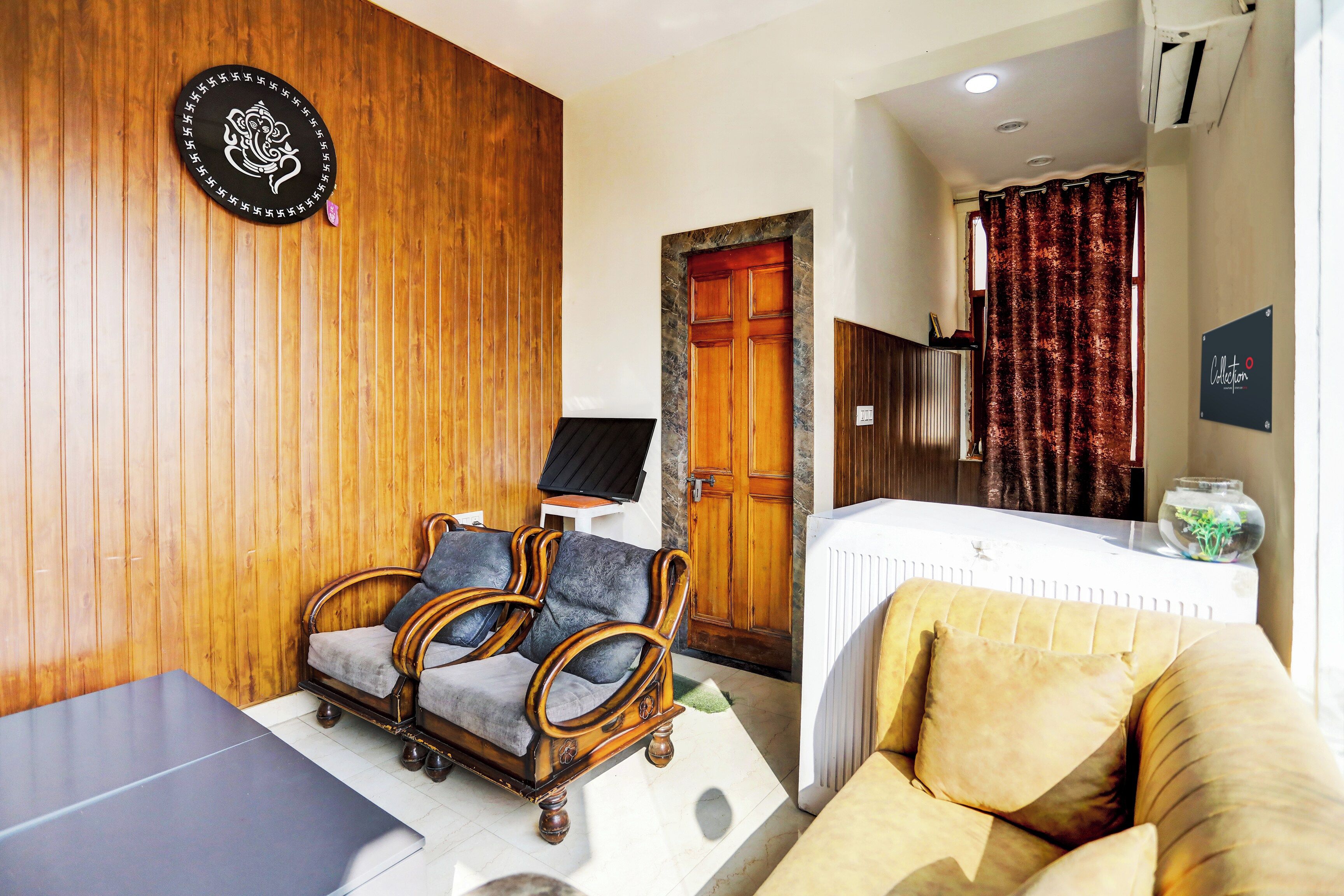 Quarto com parede de madeira, porta, balcão de recepção e dois sofás.