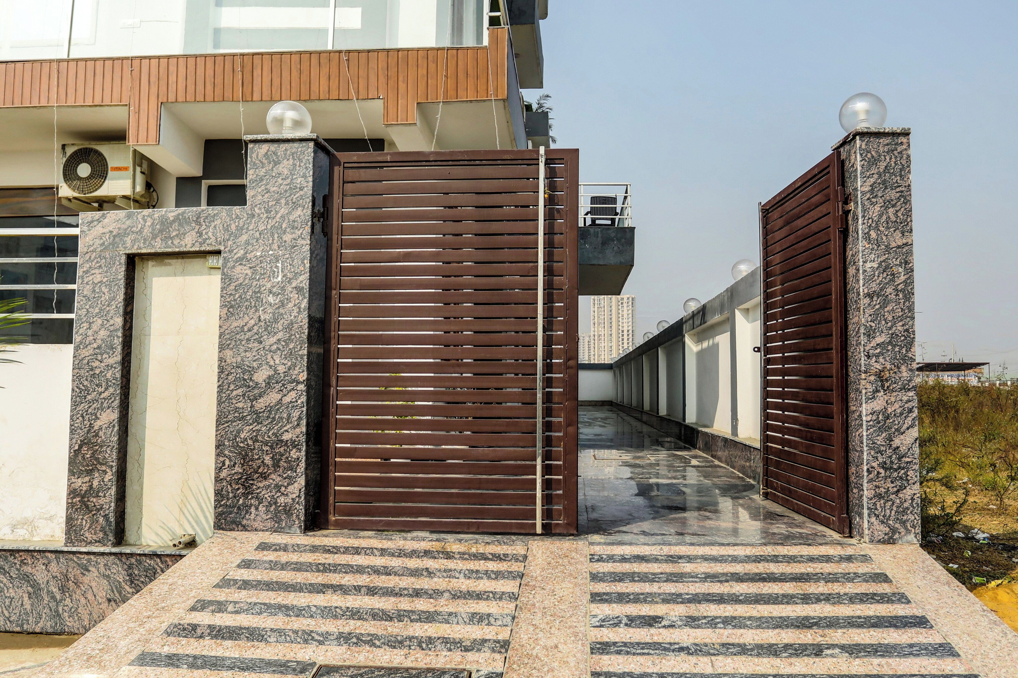 Uma entrada protegida por grades com um caminho de mármore que leva a um edifício de design moderno.