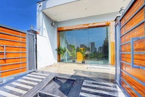 Um edifício moderno com entrada de vidro, plantas em vasos e vista para o horizonte da cidade.