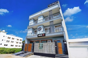 Um hotel de vários andares com uma placa grande para 'The Viraj Hotel' e a marca 'OYO'.