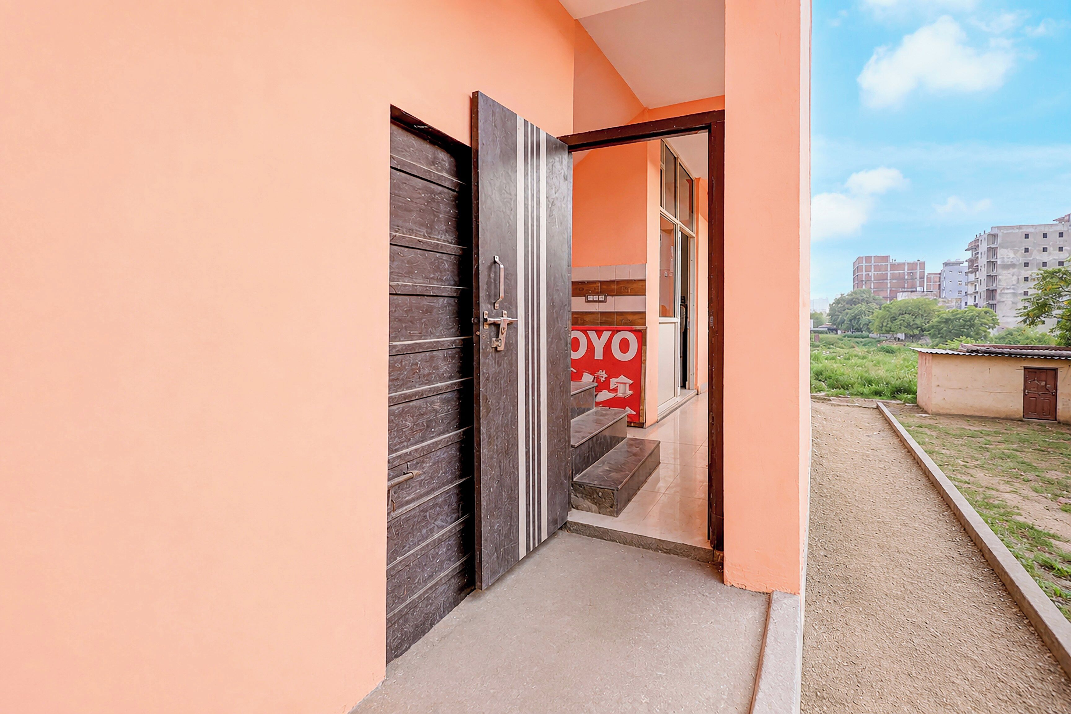Corredor com porta fechada e vista de um edifício com placa vermelha.