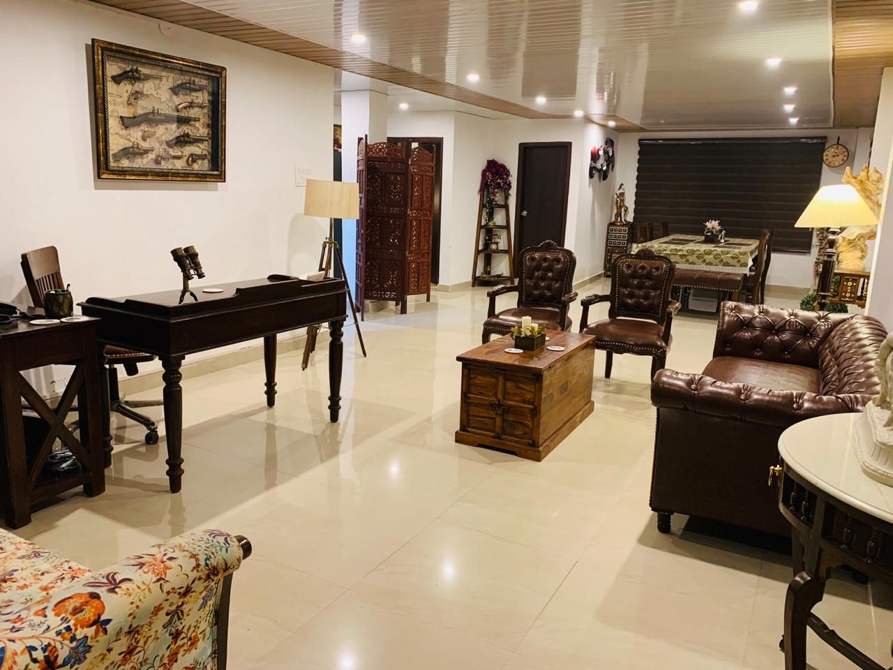 Uma sala de estar ampla, com um piano, uma mesa de centro de madeira e sofás de couro.
