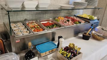 Buffet com diversas opções de comida, incluindo carnes, queijos e vegetais.