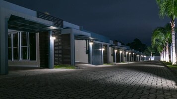 Vista noturna de um corredor de hotel com várias portas, cada uma delas numerada.