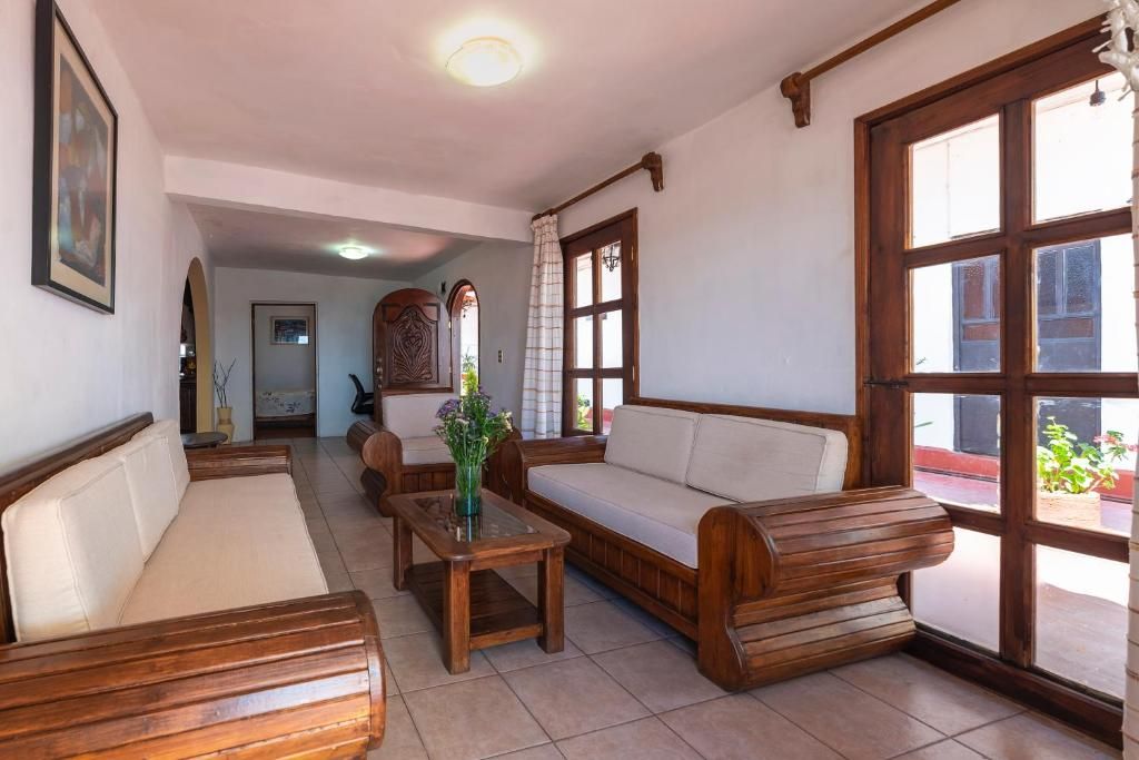 Uma sala de estar com sofá, mesa de centro de madeira e janela com cortinas.