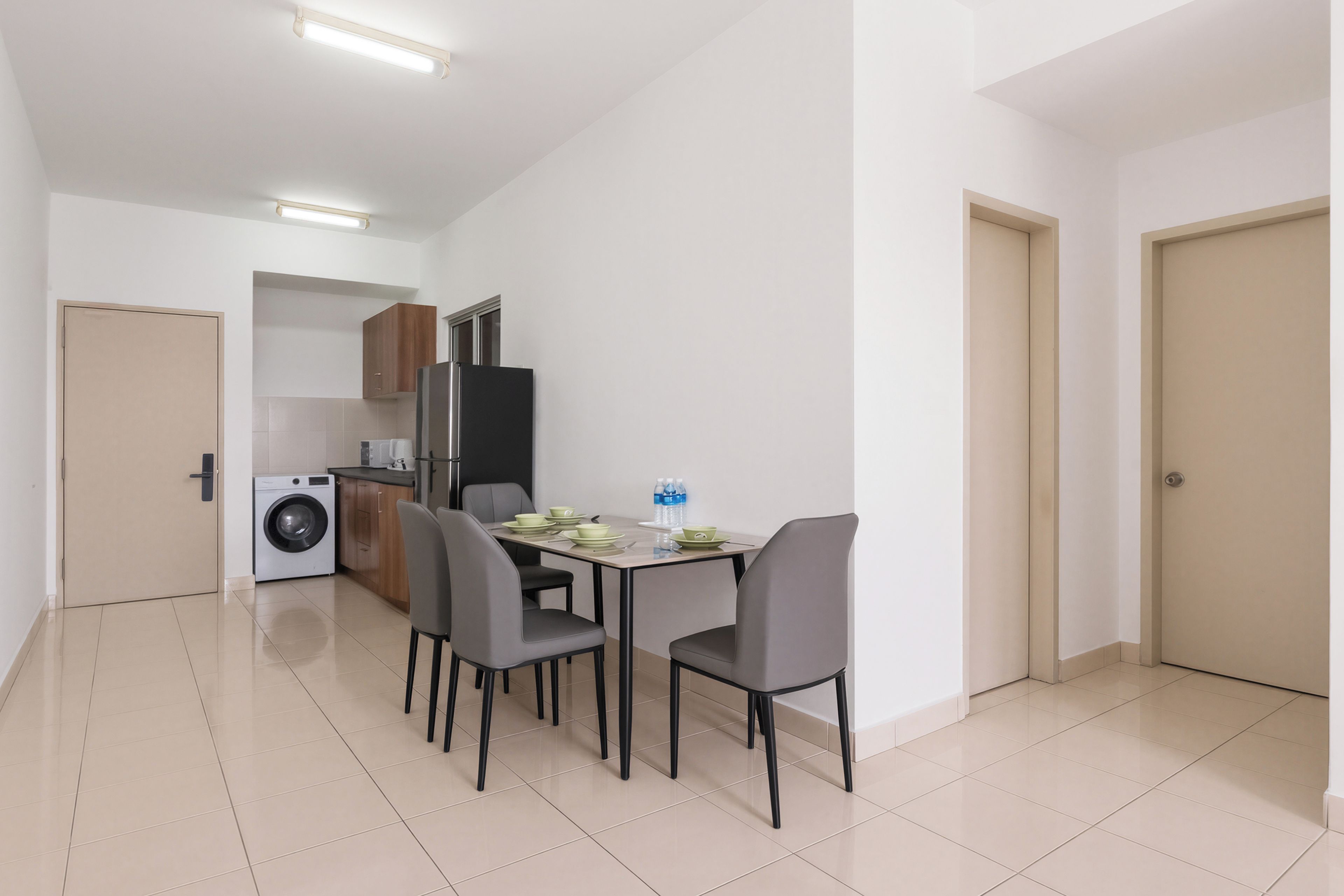 Cozinha compacta com máquina de lavar, geladeira e área de refeições com mesa e cadeiras.