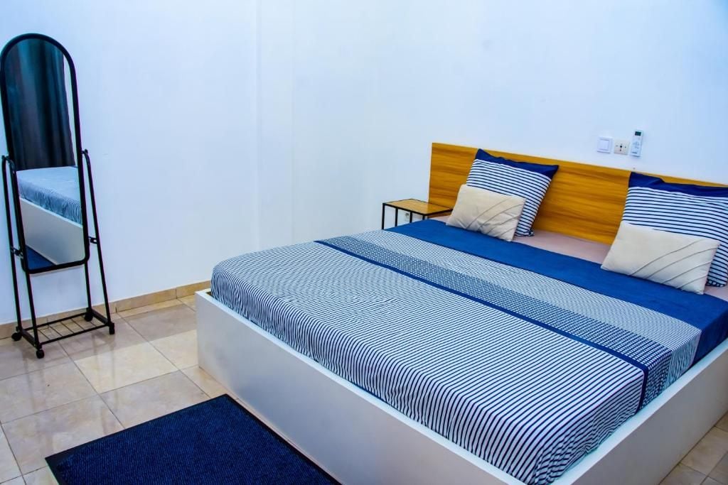 Uma cama com colcha listrada, cabeceira de madeira e duas mesas de cabeceira.