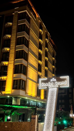 Placa de hotel com o nome 'Saadet Grand Hotel' à noite.