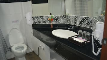 Casa de banho com sanita, lavatório e espelho.