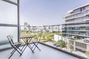 Varanda com vista para um horizonte urbano, incluindo edifícios modernos e um campo de golfe.