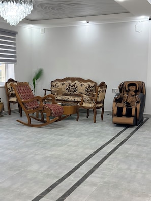 Uma sala de estar com sofá, poltrona de balanço e cadeira de massagem.