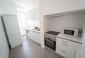 Cozinha com armários brancos, micro-ondas e fogão.