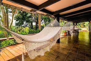 Uma rede sob uma pérgola de madeira, com vista para um jardim exuberante.