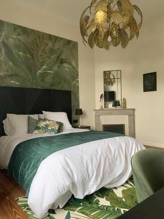 Quarto com cama, lareira, espelho e parede com padrão de folhas verdes.
