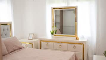 Quarto com cama, penteadeira com espelho, ventilador de teto e ar condicionado.