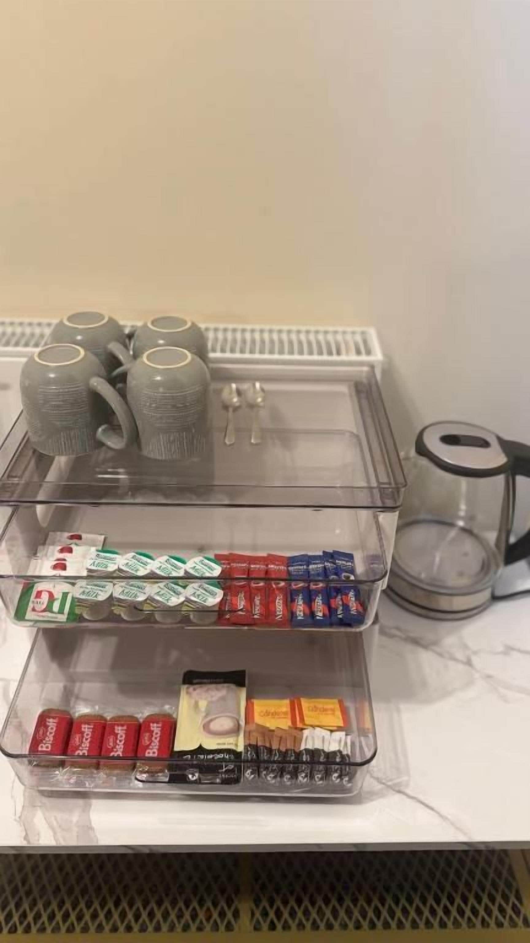 Um armário espaçoso com canecas, sachês de chá e lanches.