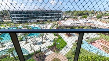 Vista de um hotel com piscina, um jardim bem cuidado e um edifício moderno ao fundo.