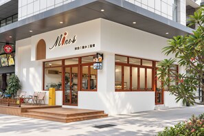 Um restaurante com fachada branca, janelas emolduradas em madeira e uma placa com caracteres chineses.