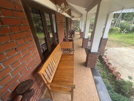 Espaço coberto ao ar livre com banco de madeira e paredes de tijolo.