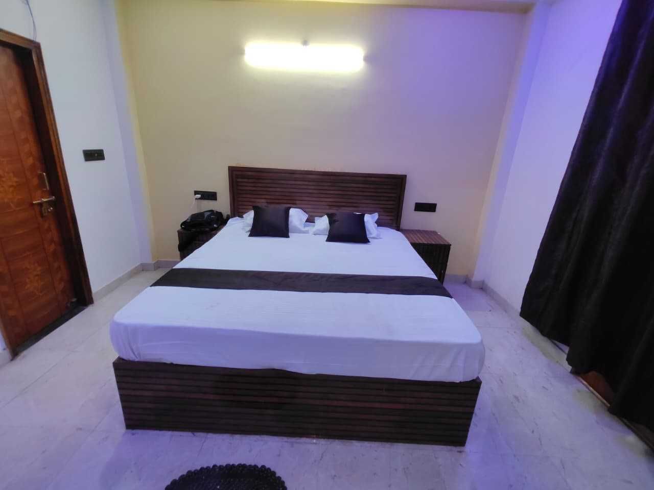 Uma cama de solteiro com cabeceira de madeira, mesa de cabeceira e luminária fixada na parede.