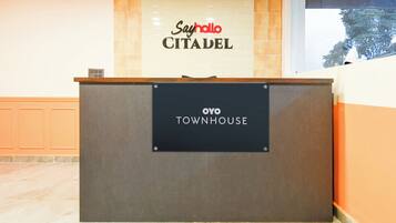Uma mesa de recepção com uma placa que diz 'Sayno Citadel' e 'OYO TOWNHOUSE'.