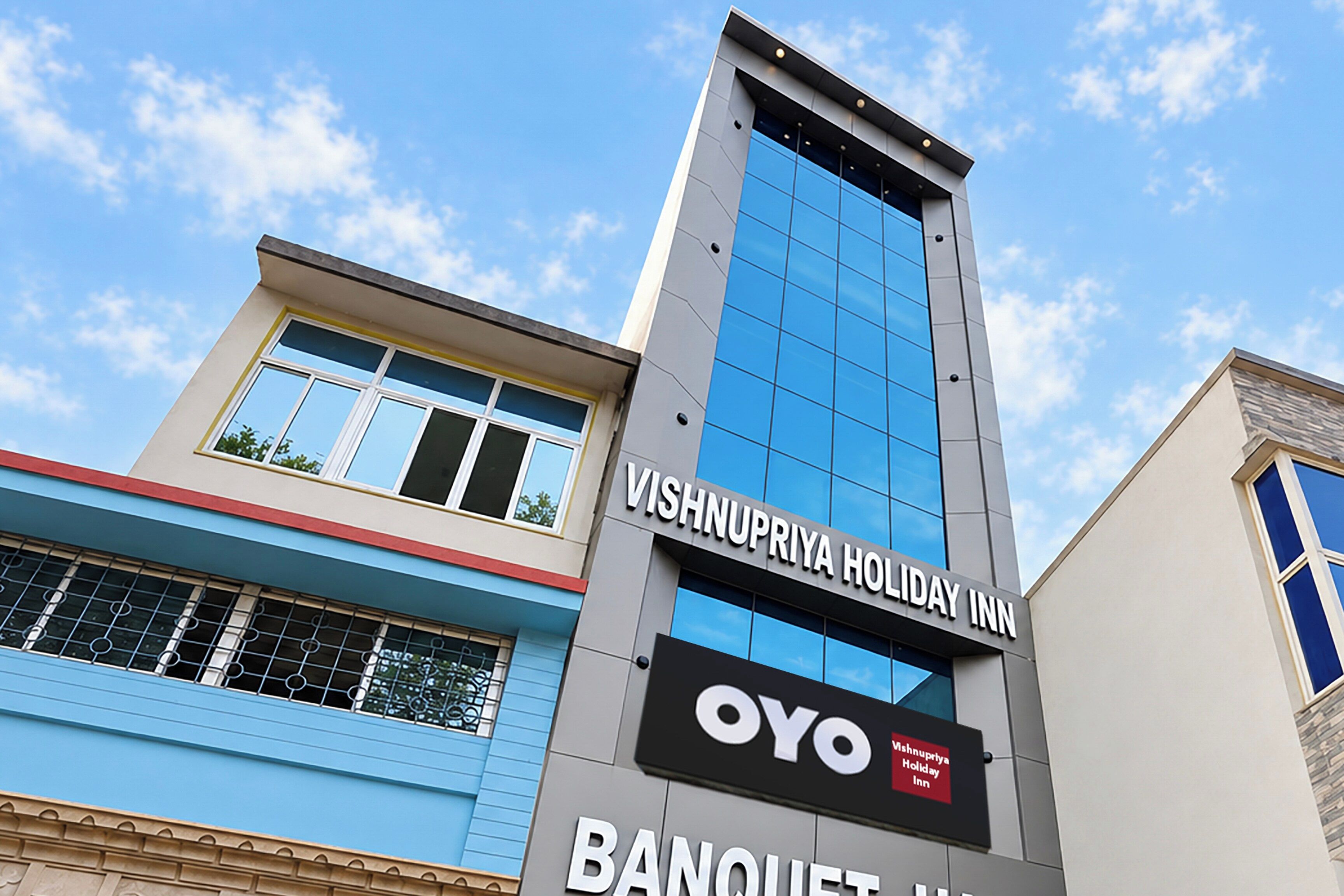 Um edifício de vários andares com uma placa de destaque para Vishnu Priya Holiday Inn e Oyo.